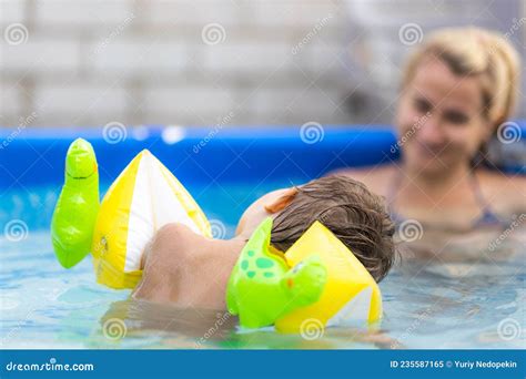 Mamãe Brinca Um Bebê Pelado Em Mangas Na Piscina Contra O Fundo De