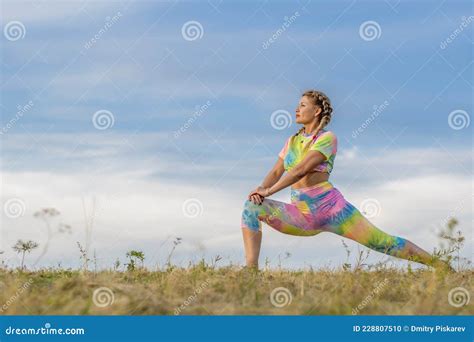 Girl Athlete In Bright Suit Does Exercise To Stretch Muscles Of Legs