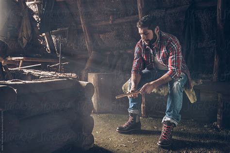 Babe Bearded Man Sitting In Wooden Rustic Alpine Cabin And Carving Wood By Stocksy