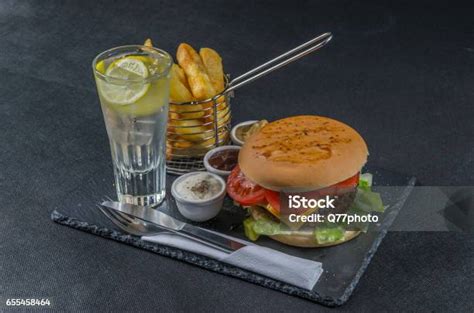 불꽃 구이 더블 스택 치즈 버거 양상추 토마토 세 소스 금속 바구니에 칩 레몬 물 구운 에 오른쪽 보기 0명에 대한 스톡 사진