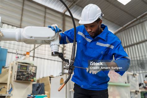 작업장에서 숙련된 로봇 팔과 함께 일하는 아프리카계 미국인 공장 남성 엔지니어 노동자 공장에서 남성 엔지니어 유지 보수 자동 로봇 팔 기계 산업용 로봇 제조 기술 30 34