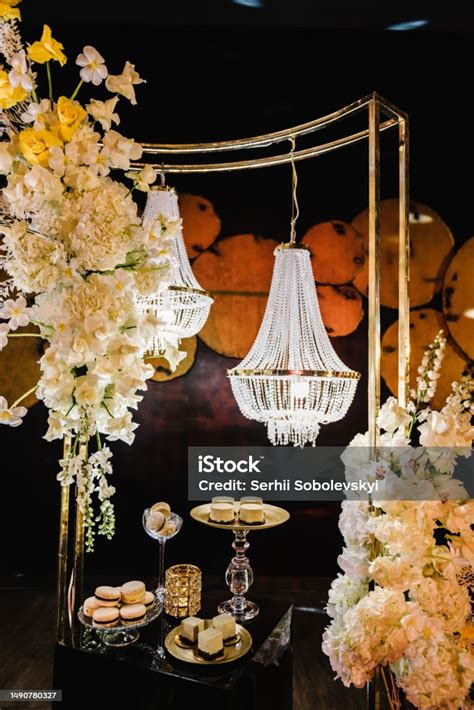 맛있는 고급 결혼식 피로연 캔디 바 사탕 디저트 테이블 큰 샹들리에가 있는 아치 홀 레스토랑의 꽃 밤에는 빛이 있는 황금빛 풍부한 인테리어 생일 침례 행사 0명에 대한 스톡