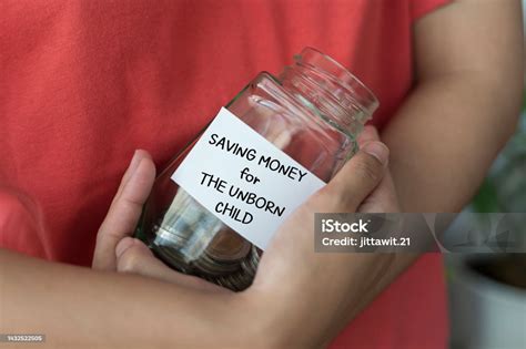 귀중한 동전으로 가득 찬 유리 항아리를 들고있는 어머니 태어나지 않은 아이를 위해 돈을 절약하십시오 통화에 대한 스톡 사진 및 기타 이미지 Istock