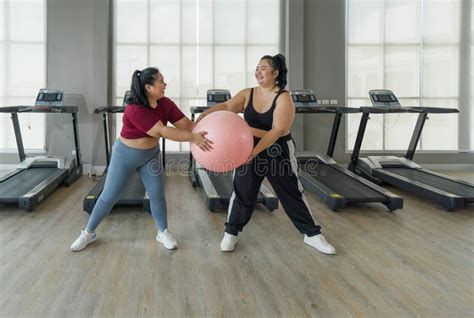 Two Overweight Women Exercises By Pass A Pink Yoga Ball Back And Forth