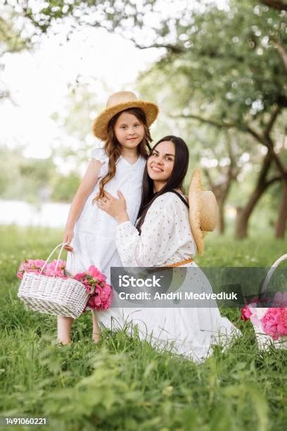 어머니의 날 여성의 날 젊은 아름다운 어머니는 녹색 여름 공원에서 어린 딸과 시간을 보내고 있다 아이를 둔 엄마는 자연에서 모란 꽃 바구니를 들고 있다 가족 모습 25 29