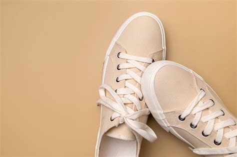 갈색 배경에 베이지색 패브릭 스니커즈가 평면적으로 놓여 있다 패션 스니커즈 끈이 달린 캐주얼 운동화 세련된 여름 봄 스니커즈 복사 공간이 있는 미니멀리즘 신발 배경 0명에