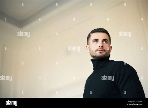 Pensive Man In A Black Turtleneck Looking Upward In A Spacious Light