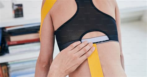 의료 사무실에서 키네시오 테이프를 적용하는 의사 Osteopath가 있는 동안 마사지 테이블에 앉아 인식할 수 없는 여성 환자의