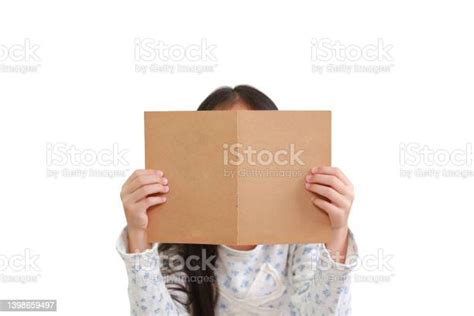 백인 어린 소녀 아이가 흰색 배경 위에 책을 읽고 있습니다 갈색 책 표지를 들고 얼굴을 숨기는 아이 클리핑 경로 아이에 대한