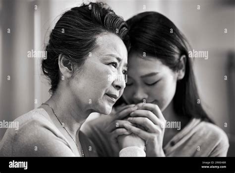 Young Asian Adult Daughter Consoling Senior Mother Living With Mental