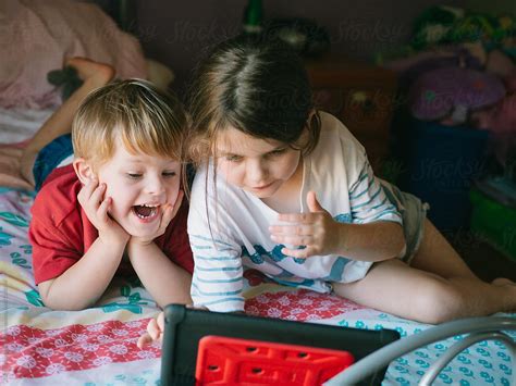 Brother And Sister Using Tablet Together On Bed Del Colaborador De