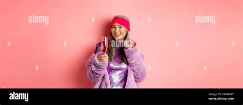 Elegant And Stylish Asian Woman In Purple Faux Fur Coat Eating Donuts