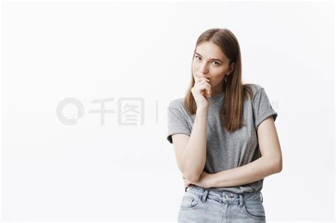 黑发高清图片 美丽的黑发白人年轻女子的特写她留着长发穿着灰色T恤和牛仔裤表情周到微笑着手握在嘴边 产品实拍免费下载 jpg格式