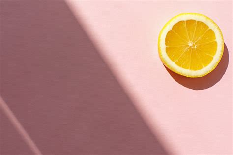 太陽の光でトレンディなピンクの用紙の背景にジューシーなレモン スライスフラット横たわっていた創造的なコントラストの夏のイメージ休暇とダイエット