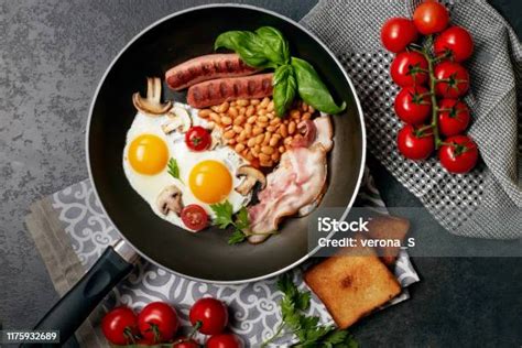 튀긴 계란 소시지 콩 토마토 버섯 베이컨 나무 배경에 토스트와 요리 팬에 영어 아침 식사 공간을 복사합니다 맨 위 보기 0명에