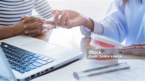 치과 의사는 치과 진료소 사무실에서 치아 모델 틀니 및 탐색기 거울 도구를 사용하여 환자에게 치아 질환 치료를 보여주고 설명합니다 헬스케어 개념 개념에 대한 스톡 사진 및