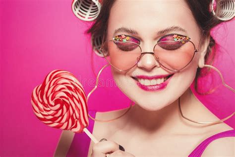 Cheeky Girl With Sweets On Tongue And Glass With Candies Posing On Pink