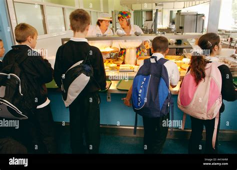 School Pupils Queue At Hot Counter Waiting To Be Served By Kitchen Staff In School Refectory Uk