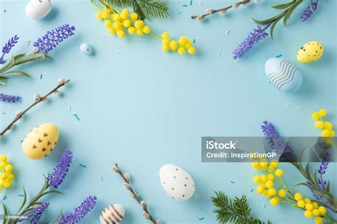 파스텔 톤의 달걀 노란색 미모사 라벤더 꽃으로 장식된 부활절 크리스마스 장식 연한 파란색 배경에 나뭇가지와 녹색 단풍과 같은 자연 요소가 배치되어 축제 미학을 연출합니다 4