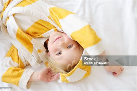 목욕 가운을 입은 귀여운 아이의 초상화가 깨어난 후 침대에 누워 있다 가정용 아동복 아침 일과를 보내고 유치원에 갈 준비를하는