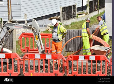 Group Of Workers Installing Coil Of Fibre Optic High Speed Broadband