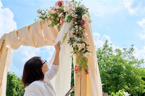 꽃과 식물 직물로 아치장식 웨딩 아치 근처의 디지털 태블릿을 가진 여성 주최자 소유자 개화기에 대한 스톡 사진 및 기타 이미지