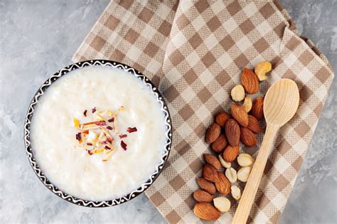회색 배경에 견과류가 있는 인도 쌀 Kheer 콘크리트 위에 쌀 푸딩과 린넨 냅킨이 있는 그릇 상위 뷰 0명에 대한 스톡 사진