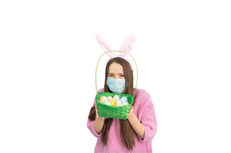 부활절 달걀 사냥 토끼 귀와 스튜디오의 흰색 배경에 고립 된 미소 장식 계란의 바구니와 의료 마스크에 행복한 소녀 16 17