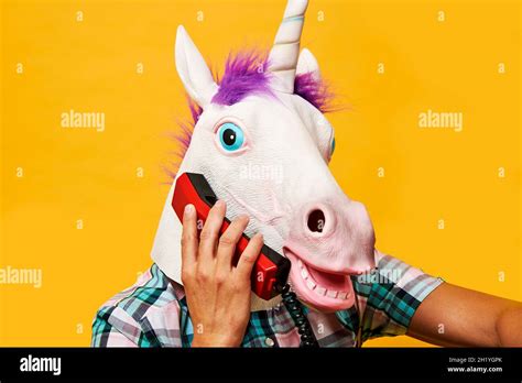 Closeup Of A Young Man Wearing A Unicorn Mask Talking On A Colorful Red