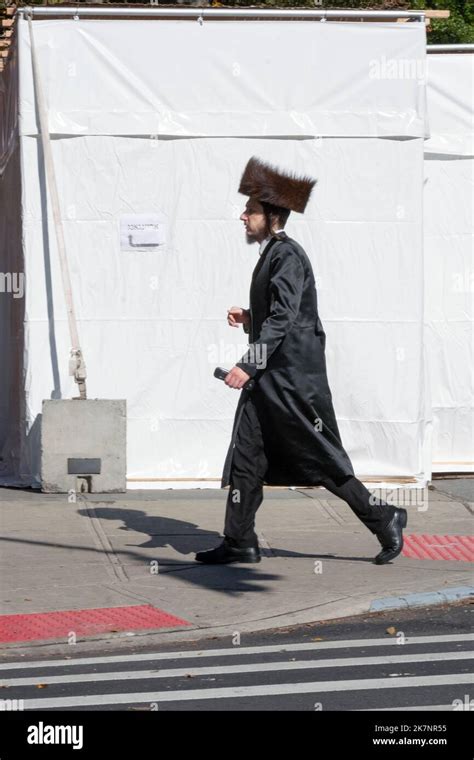 A Hasidic Jewish Man Walks Past A Sukkah Wearing A Shtreimel Fur Hat