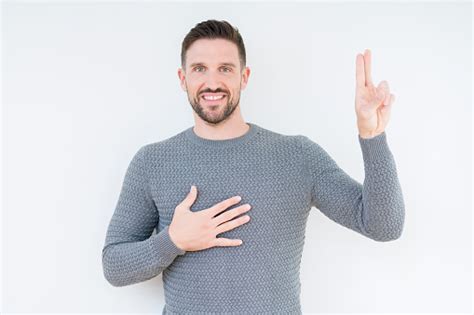 격리를 통해 캐주얼 스웨터를 입고 젊은 잘생긴 남자 배경 Swearing 가슴에 손가락 손으로 충성도 약속 선 서를 만들고