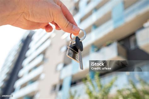배경에 우뚝 솟은 높고 세련된 현대식 건물 앞에서 집 열쇠를 들고 있는 사람 개념에 대한 스톡 사진 및 기타 이미지 개념 거리 건물 외관 Istock