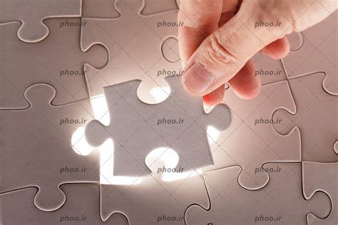 عکس با کیفیت دست در حال قرار دادن آخرین قطعه پازل در پس زمینه سفید
