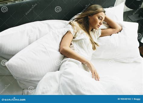 Mujer Joven Que Miente En Cama Con El Lino Blanco Foto De Archivo Imagen De Resto Cansado