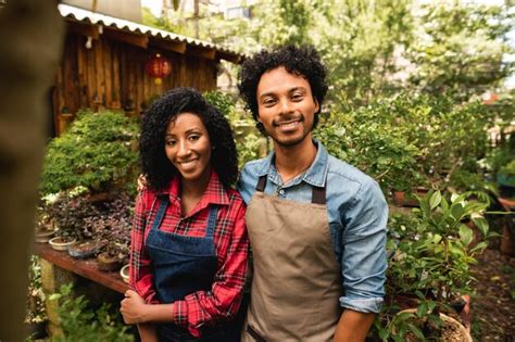 Premium Photo Portrait Of Couple Standing And Smiling At Plant Nursery