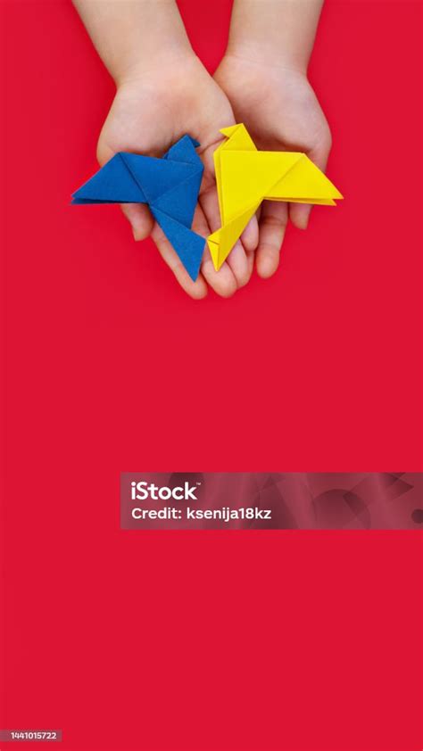 빨간색 배경에 아이들의 손에 있는 우크라이나 국기의 색상의 노란색과 파란색으로 종이접기 종이로 만든 두 마리의 비둘기 수직 169 아이에 대한 스톡 사진 및 기타 이미지