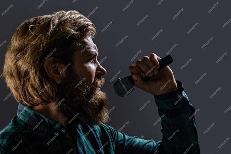 Premium Photo Man With A Beard Holding A Microphone And Singing