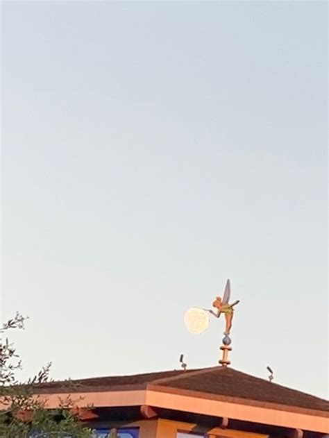 An Airplane Flying Over A Building With A Clock On Its Roof And A