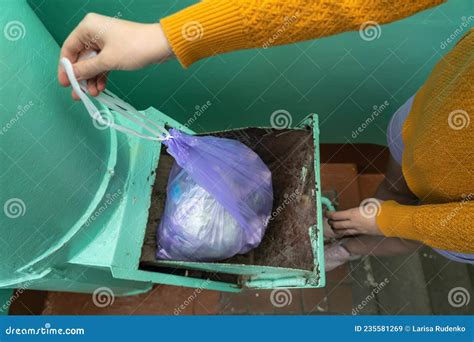 A Woman`s Hand With A Garbage Bag Opens The Hatch Of The Garbage Chute