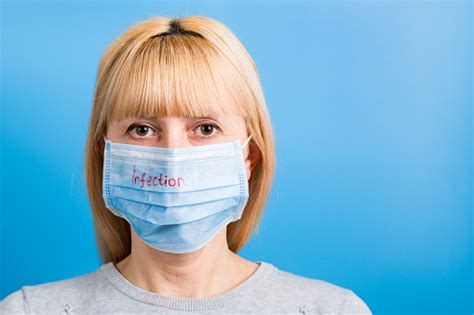 파란색 배경에 감염 텍스트와 의료 마스크를 착용 하는 여자의 초상화입니다 코로나 바이러스 개념 호흡기 보호 간호사에 대한 스톡