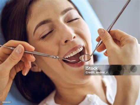 치과 진료소에서 치과 의사에 의해 검사되는 웃는 갈색 머리 여자 환자의 입 근처에 치과 기구를 들고 의사의 손 건강한 치아 및 의학 개념 25 29세에 대한 스톡 사진 및