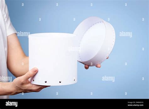 Woman Hands Holding White Round Cardboard Box And Open Cap On Light Blue Background Mock Up