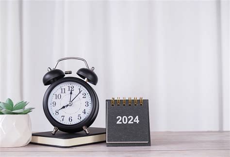 2024년 달력이 있는 크리에이티브 데스크 하드커버 책의 검은색 알람 배경에 흰색 커튼이 있는 선인장 텍스트를 위한 복사 공간