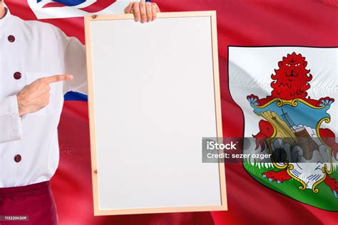 요리사는 버뮤다 국기 배경에 빈 화이트 보드 메뉴를 들고 텍스트에 대 한 균일 한 포인팅 공간을 착용 요리 Bermuda Flag에 대한 스톡 사진 및 기타 이미지 Istock