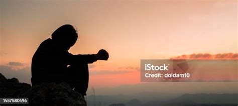 기독교 예배 개념을 가진 신앙 기독교의 깃발 영적 기도는 흐릿한 아름다운 일몰 배경으로 태양 위에 빛납니다 일몰에 대한 희망적인 축복으로 신에게 기도하는 여자 성공에 대한