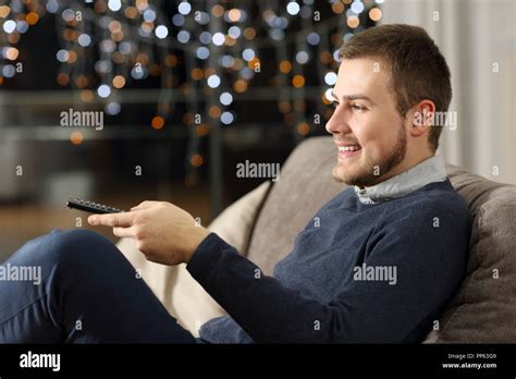 Happy Man Watching Tv At Home In The Night Sitting On A Couch In The