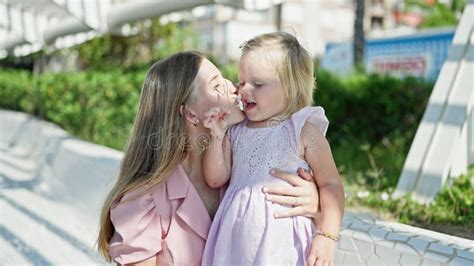 Cheerful Caucasian Mother And Babe Share A Sweet Kiss While Sitting On A Park Bench Holding