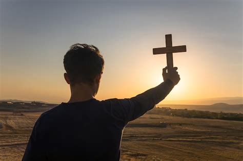 Homem Segurando Cruz Ao Pôr Do Sol Foto Premium