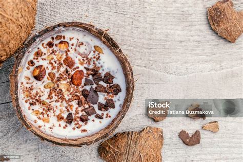 오트밀 견과류 말린 과일 강판초콜릿으로 만든 코코넛 밀크와 그래놀라는 나무 배경에 코코넛 껍질로 만들어졌습니다건강한 음식과 건강한 디저트의 Сoncept 텍스트 공간 복사