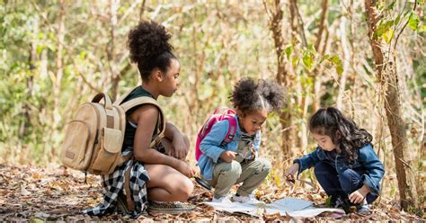 다양성의 그룹 여름 화창한 날에 숲 산에서 함께 배낭 하이킹을 하는 어린 소녀 친구들 세 아이가 앉아서 숲을 탐험하는 지도를 보며 즐거운 야외 활동을 하고 있습니다 사진